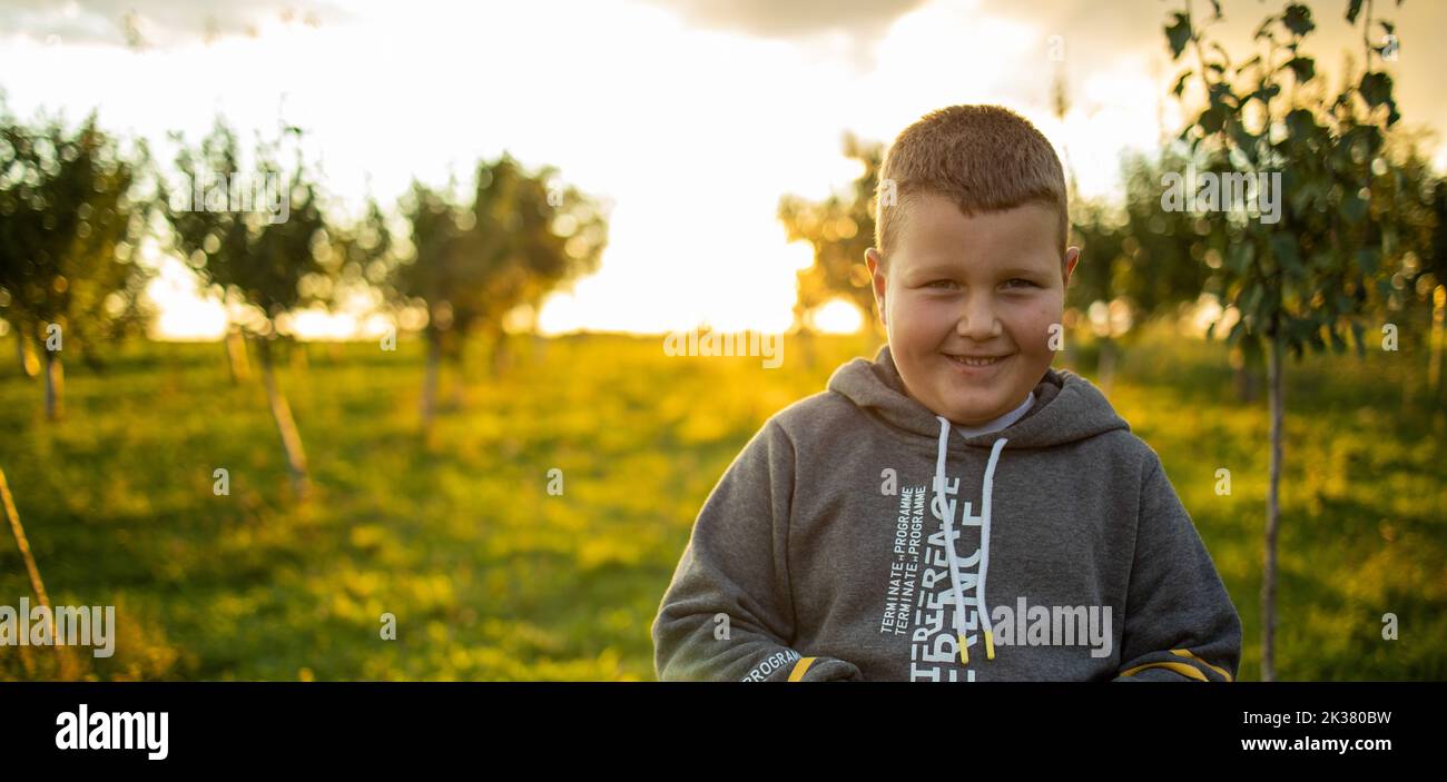 The boy looks at the camera and smiles. The boy poses in a village ...