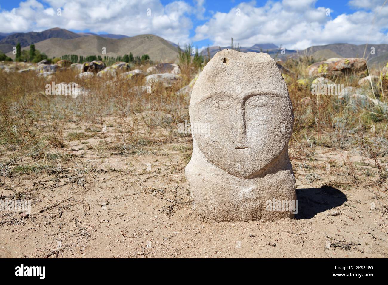 Ancient turkic stone statue depictures a man against mountains. VII-X ...