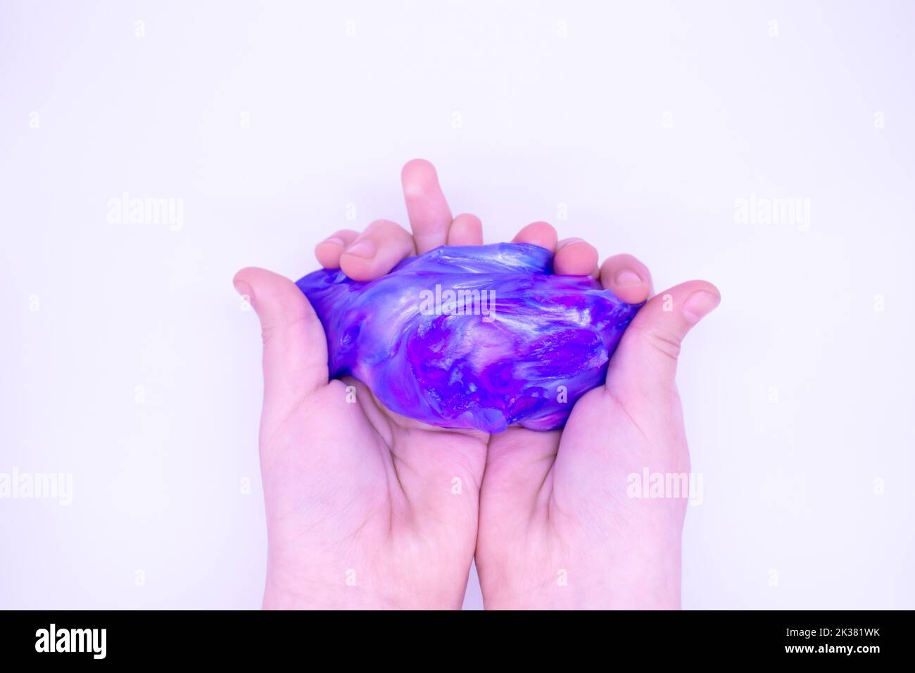 Two-color blue and pink slime in someone hands on a white background ...