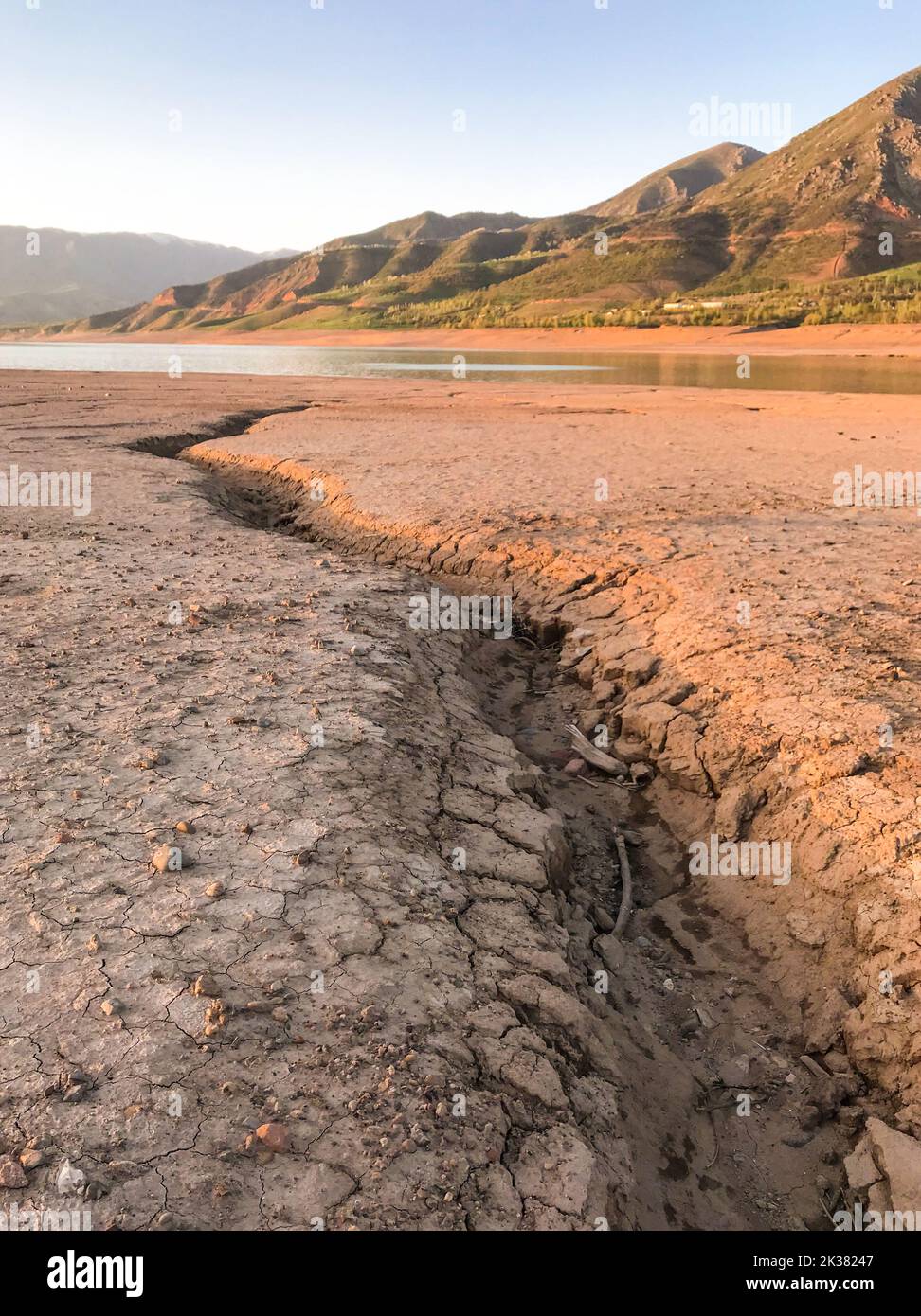 Beautiful landscape with setting sun: mountains, lake, cracked earth ...