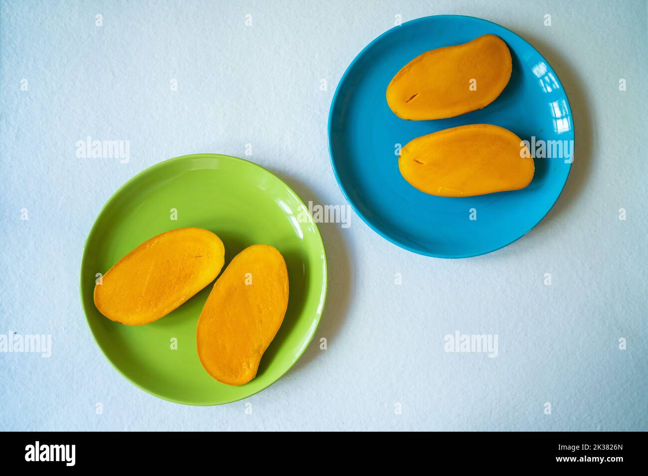 A top view of the tasty ripe mango slices on the blue and green plates ...