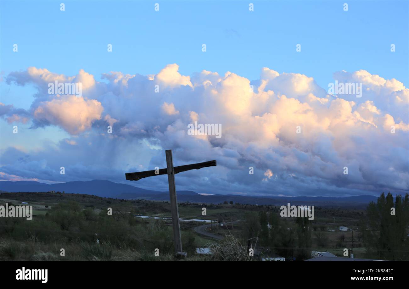 A wooden cross in the field with trees under the cloudy sky Stock Photo ...
