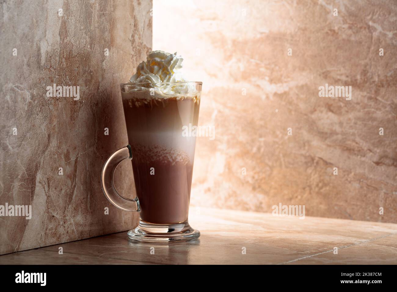 Milk coffee cocktail with whipped cream on a beige ceramic table. Copy ...