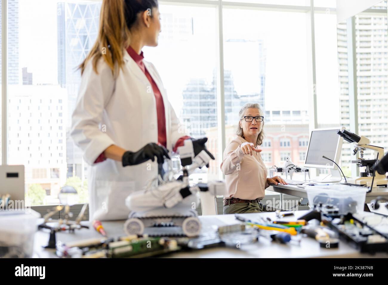 Female engineers talking and assembling robotics in highrise office Stock Photo - Alamy