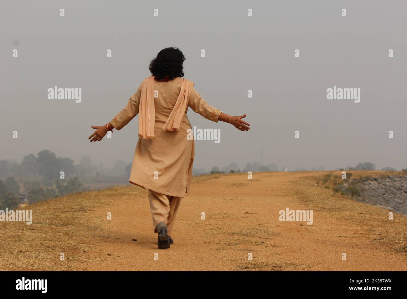 A beautiful shot of a woman on a field on a gloomy day enjoying freedom ...