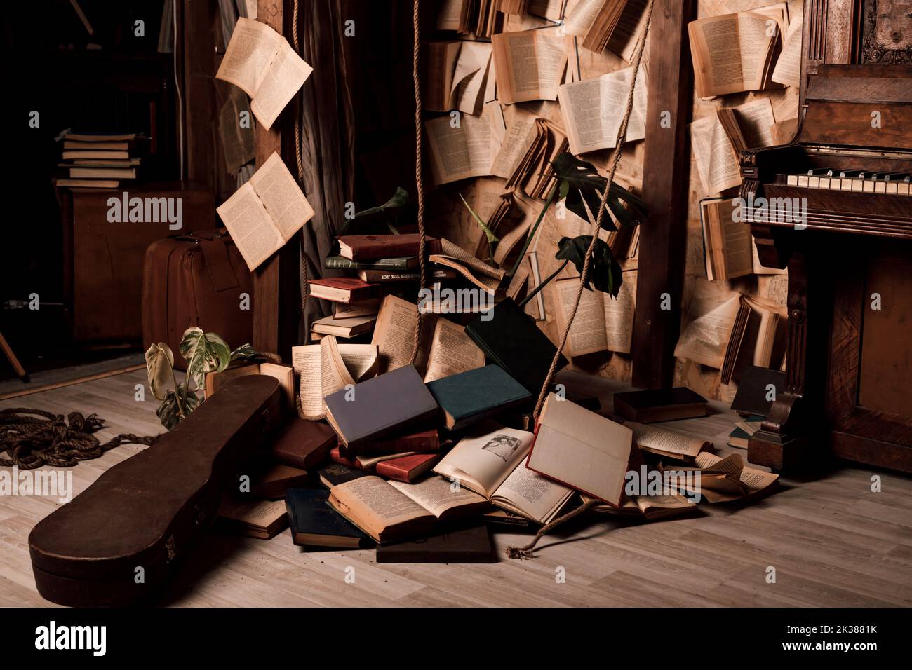 Books lie on the floor and hang on the walls in a dark room. Retro ...