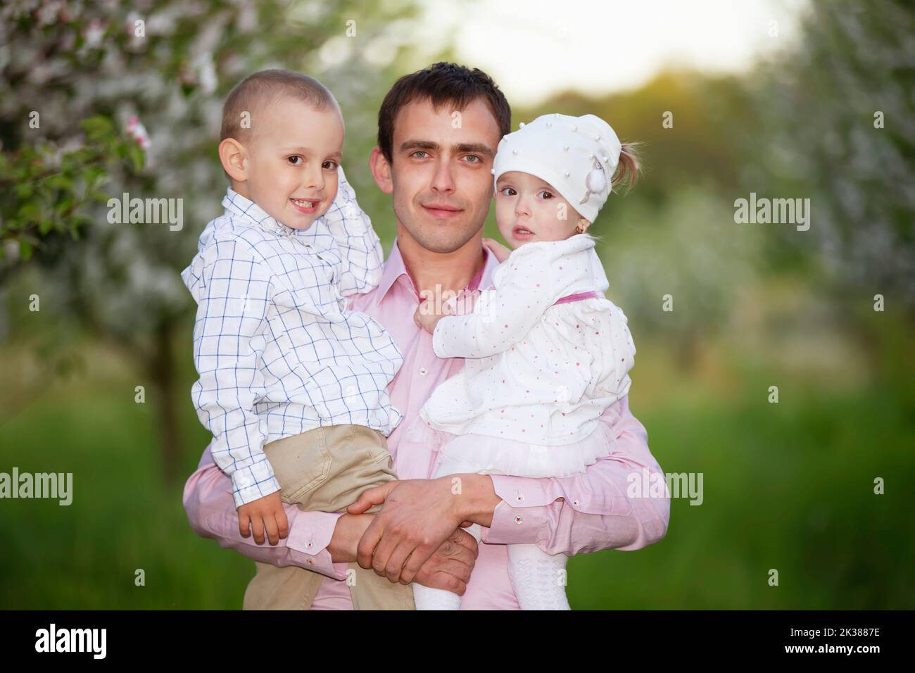 A happy father holds his son and daughter in his arms. Father's Day ...