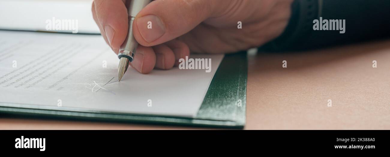 Low angle closeup view of casucasian male hand signing a document or ...