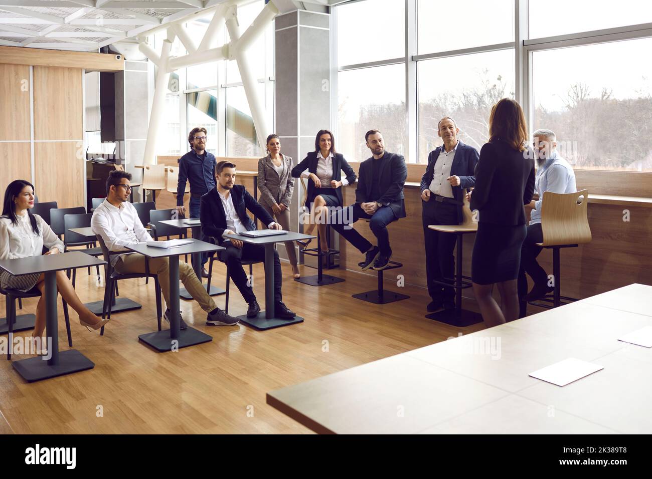 Variety of business people listen to female business coach at ...
