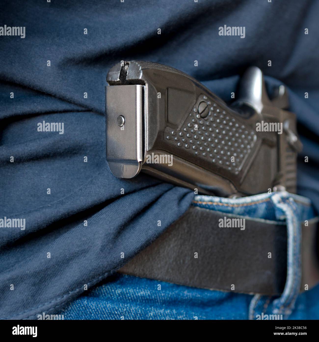 Black traumatic gun behind a black belt Stock Photo - Alamy