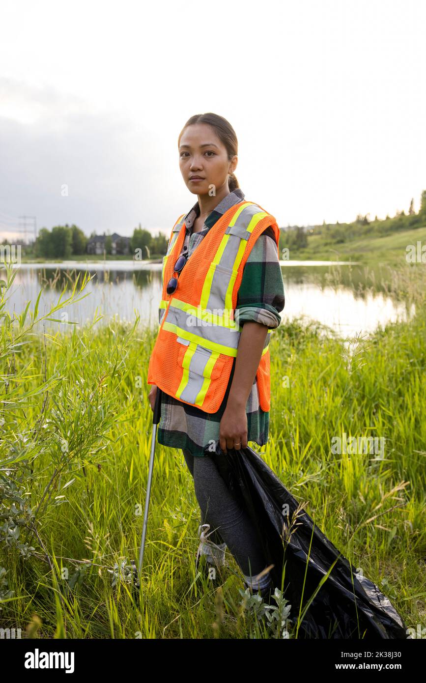 Portrait of woman litter picking next to lake Stock Photo - Alamy