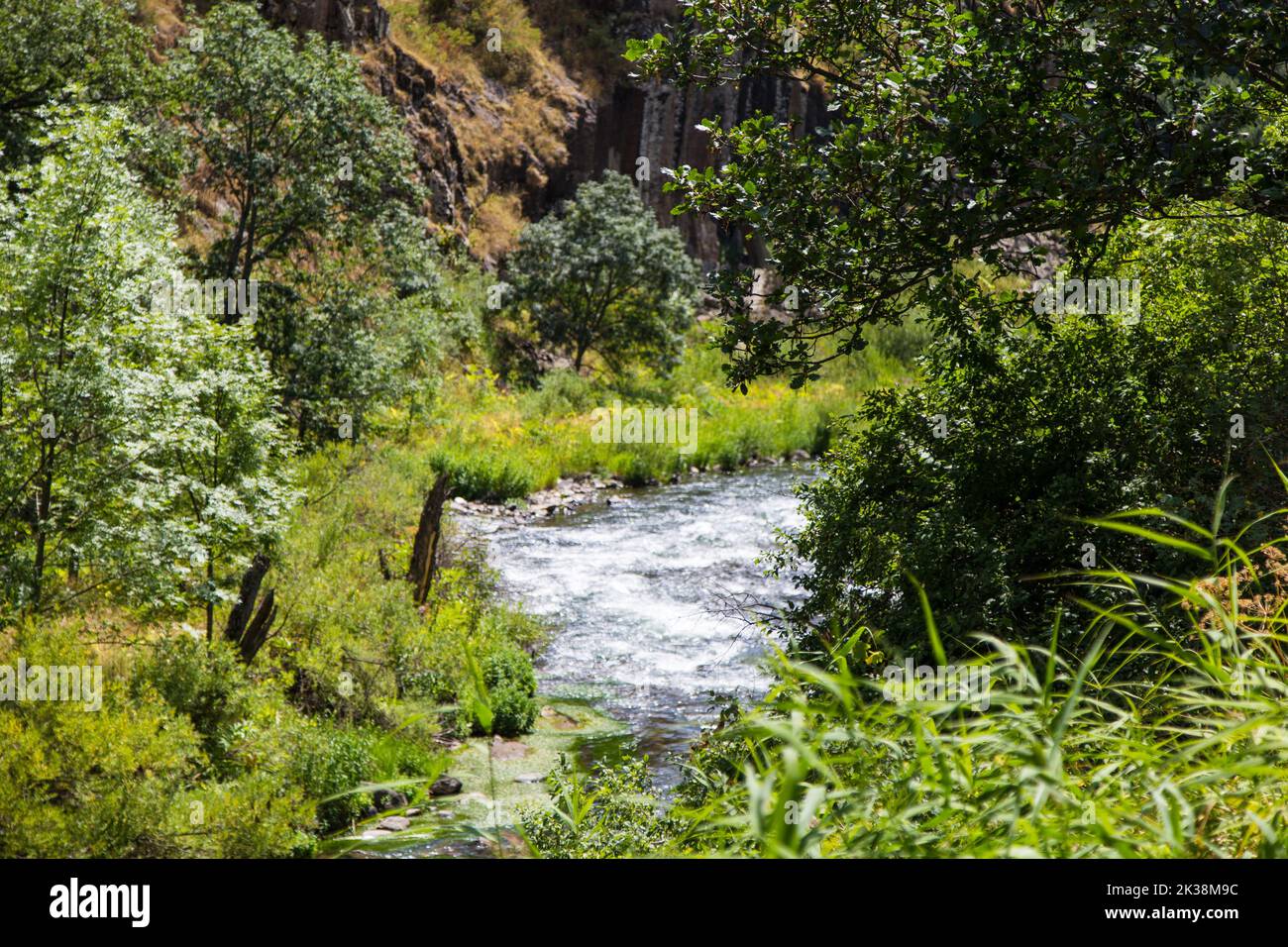 An aerial view of flowing river surrounded by rocks and trees Stock ...