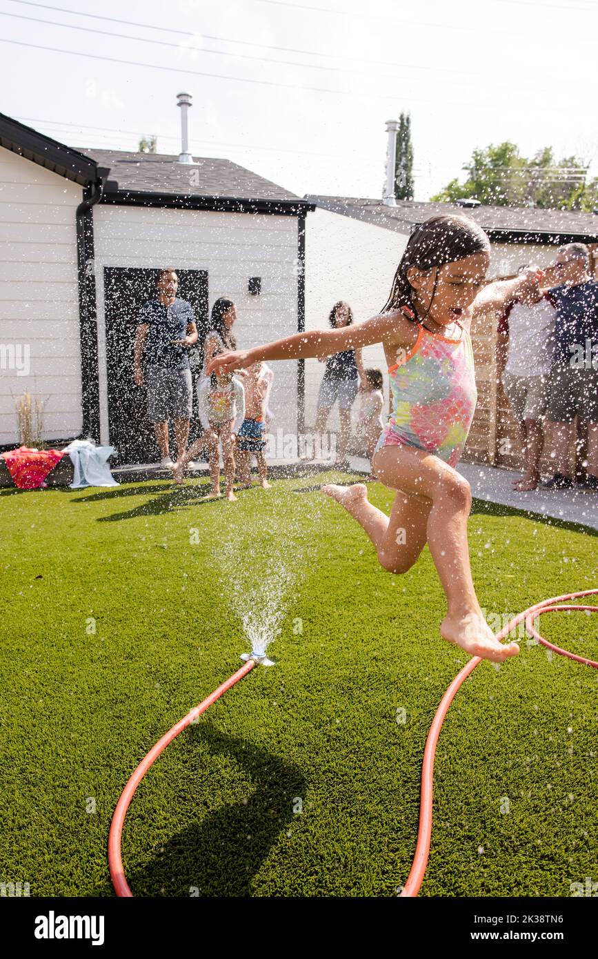 Girl jumping through lawn sprinkler hi-res stock photography and images ...