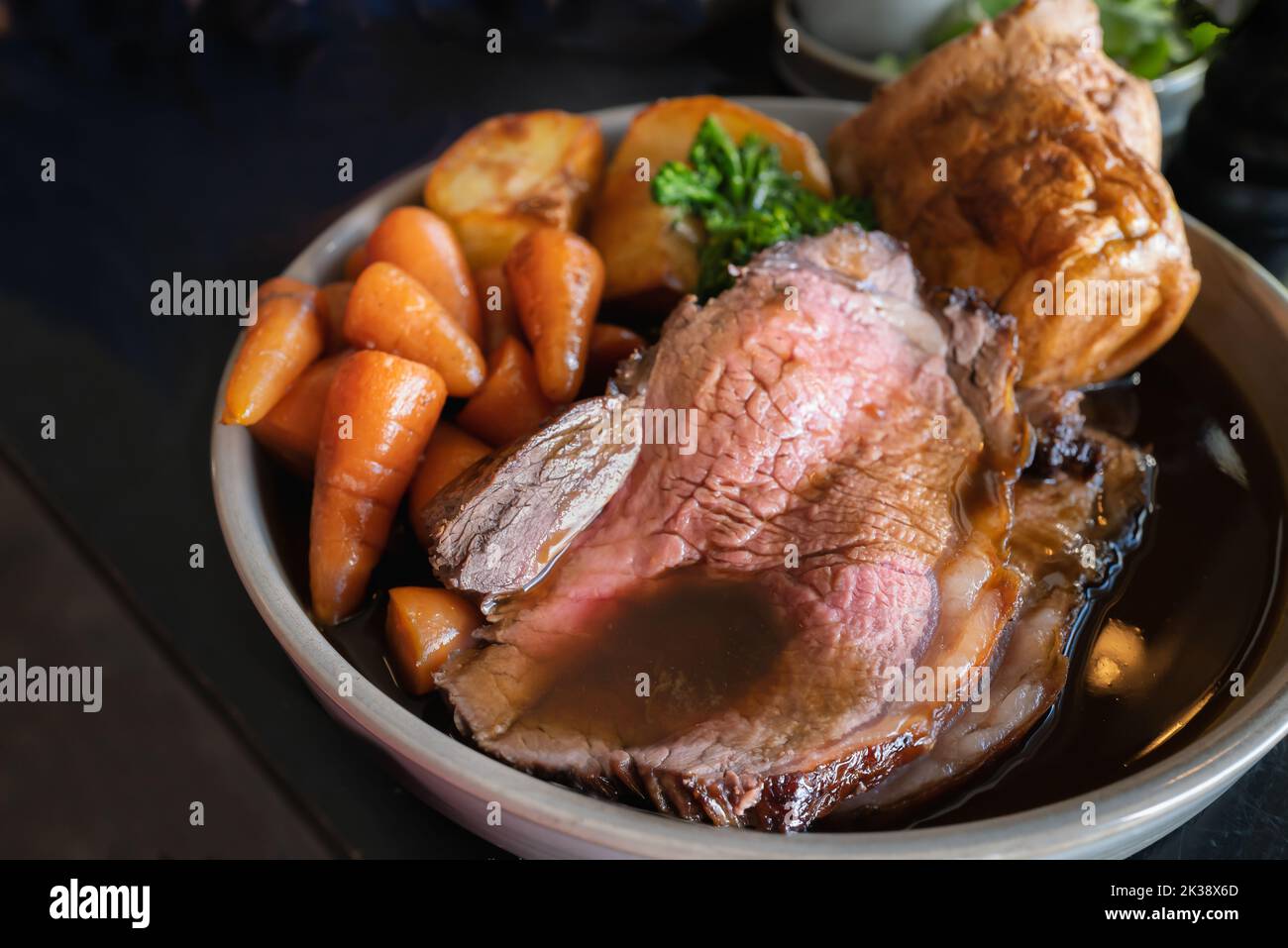 Roast beef slices on a plate with carrots, roast potatoes, a Yorkshire ...