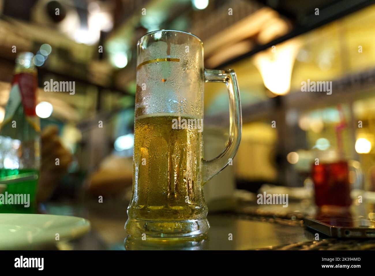 A misted glass in the beams of the interior lighting of the bar. Close ...