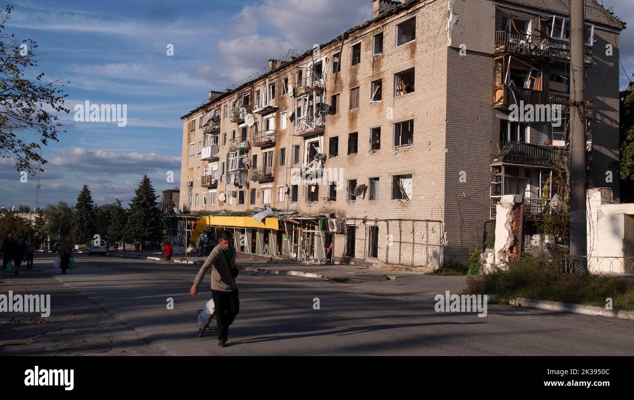 People walk past destroyed buildings in Izium, Ukraine. Residents of ...