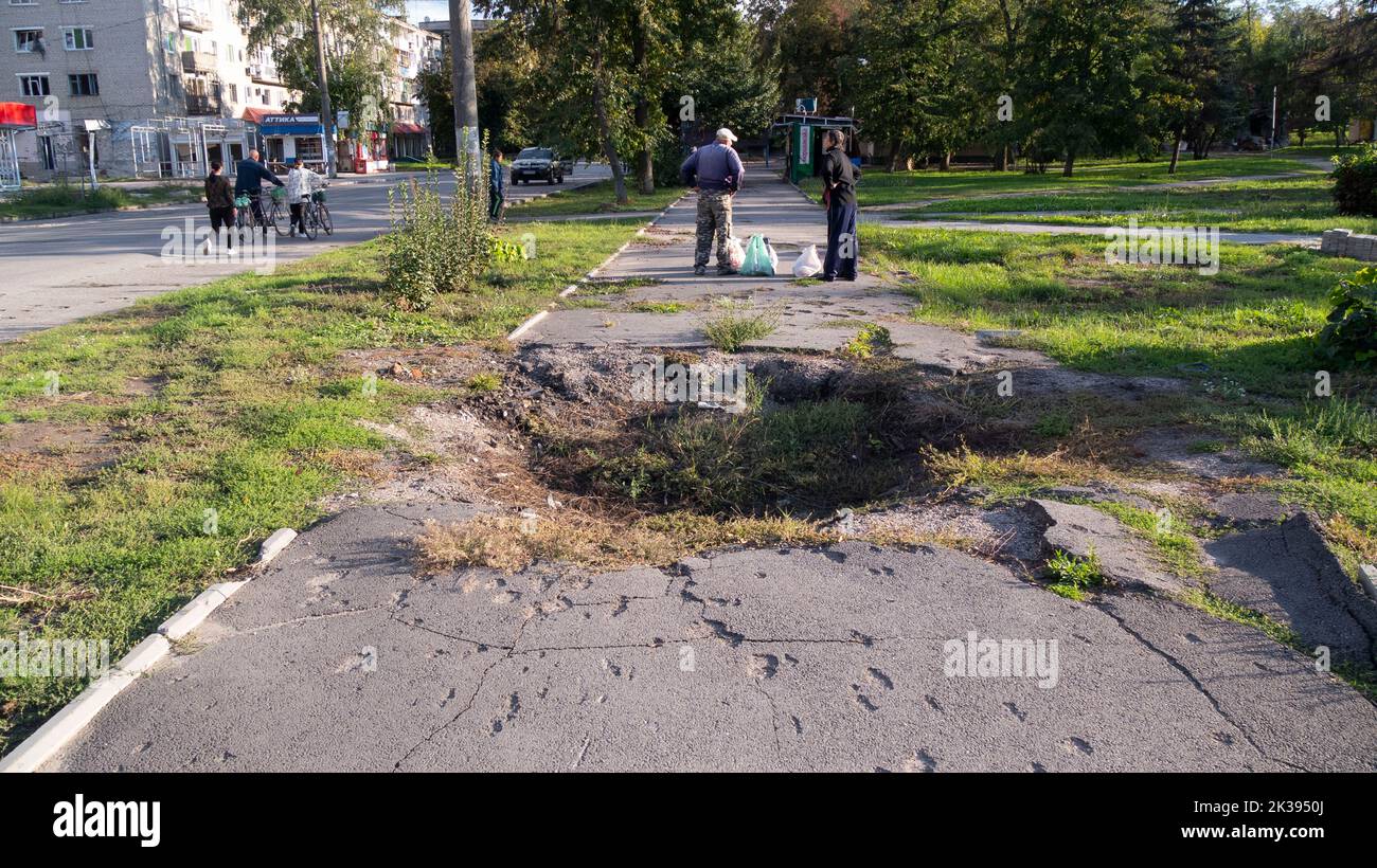 People walk past crators in Izium, Ukraine. Residents of Izium have ...