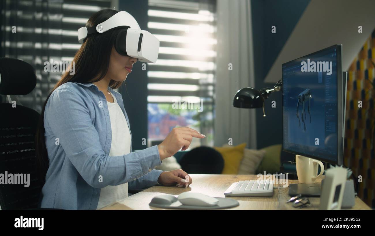 Asian woman sitting at the table at home office and using VR headset to ...