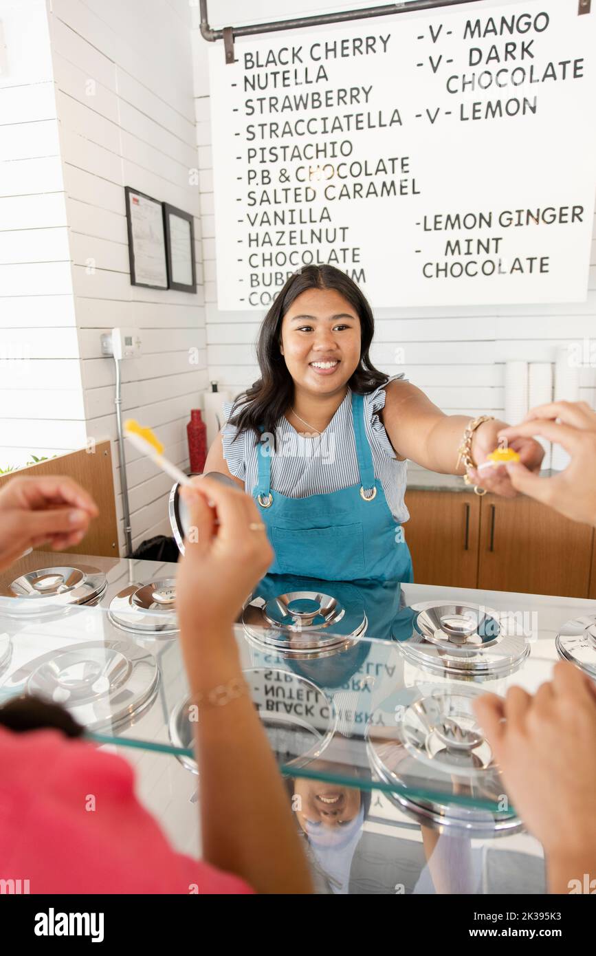Worker serving ice cream tasters to customers at service counter Stock ...