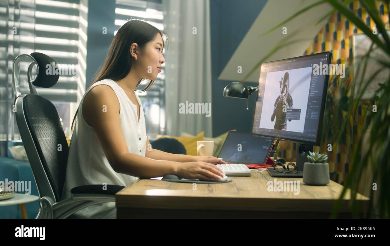 Asian woman creating 3D model of video game character in professional program using computer and ...