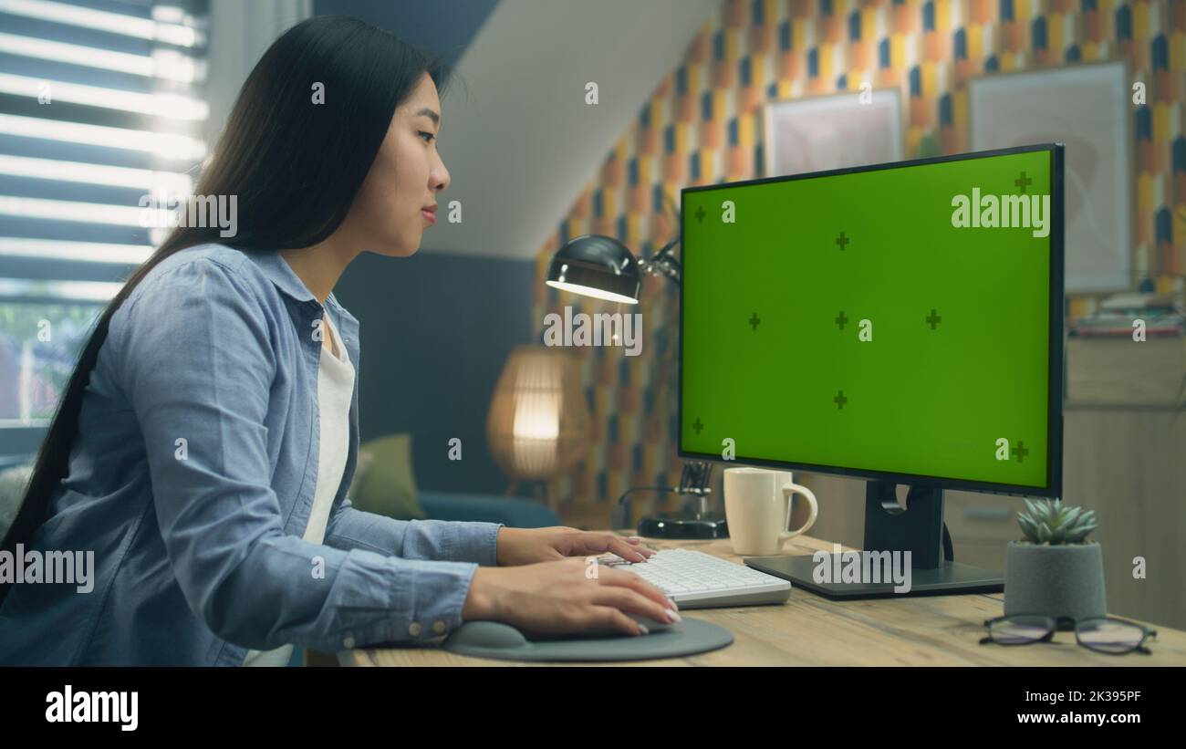 Asian woman sitting at the table and looking at screen of personal ...