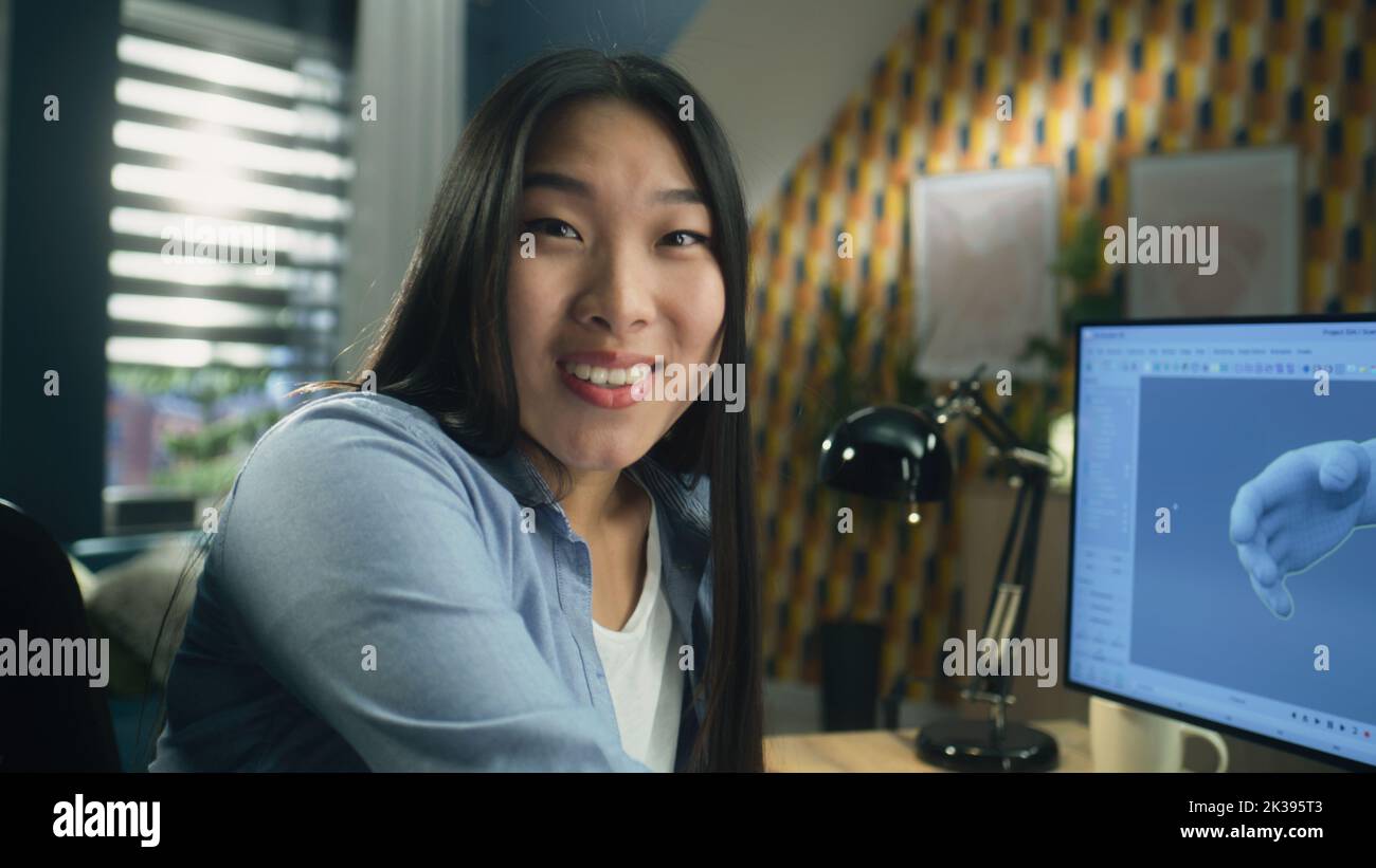 Surprised asian woman rejoicing and looking at camera while sitting at ...