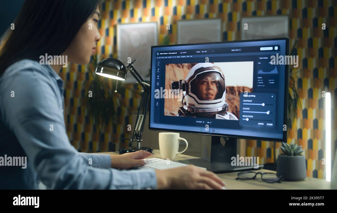 Female asian freelancer editing picture with astronaut on computer in ...