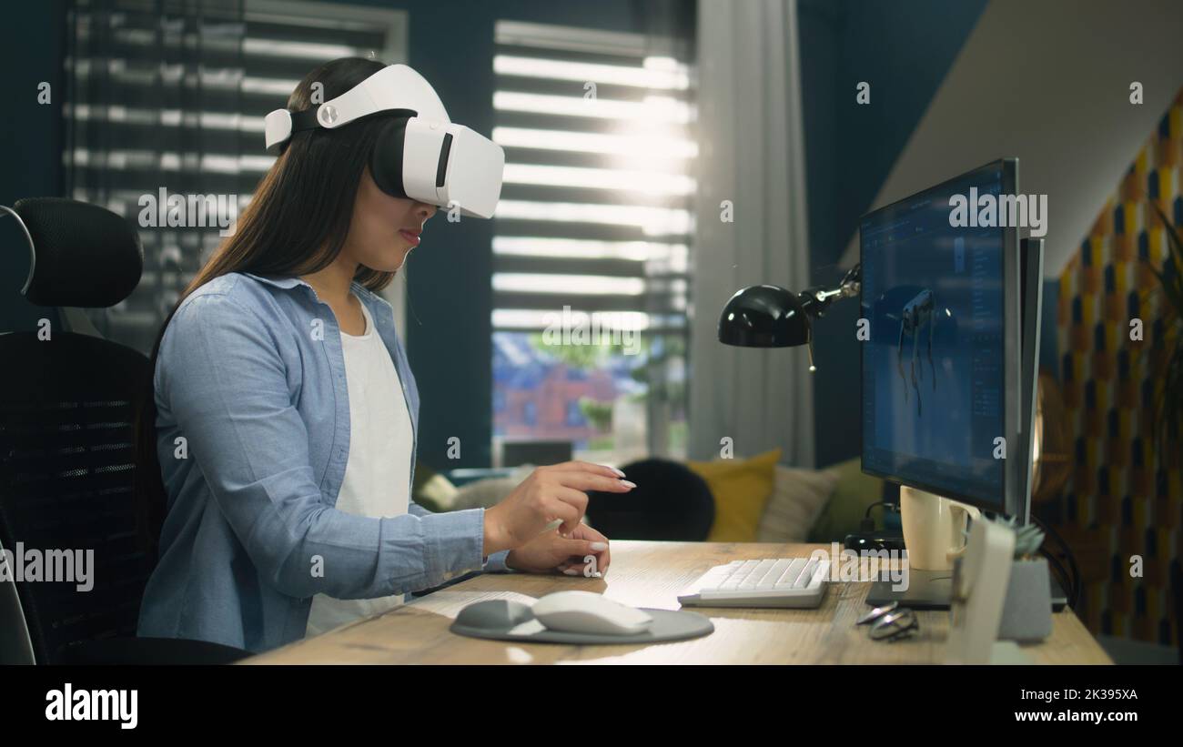 Asian woman sitting at the table at home office and using VR headset to ...