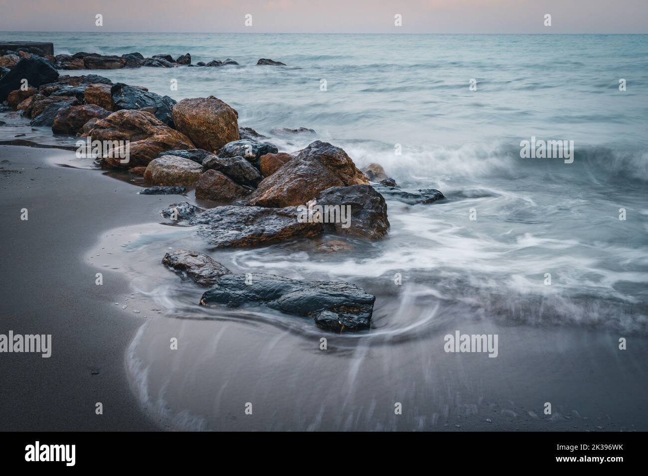 A long exposure effect of ocean waves hitting the sandy beach with ...