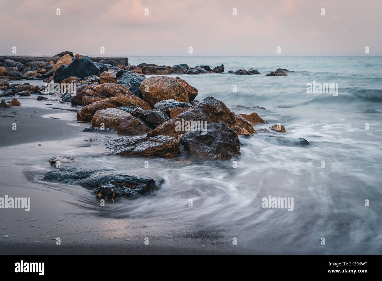A long exposure effect of ocean waves hitting the sandy beach with ...