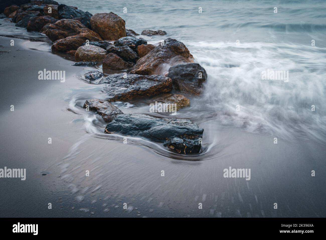 A long exposure effect of ocean waves hitting the sandy beach with ...