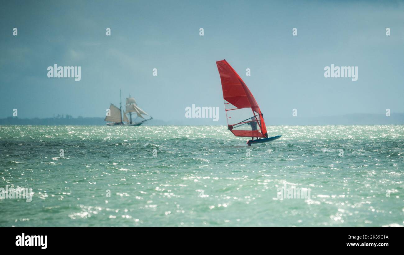 A man rides a hydrofoil windsurfer in the sea off Takapuna Beach ...
