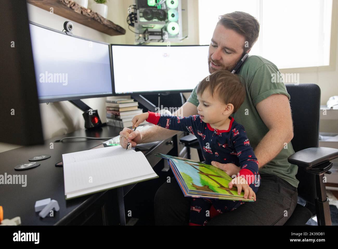 Busy father working from home with toddler son on lap Stock Photo - Alamy