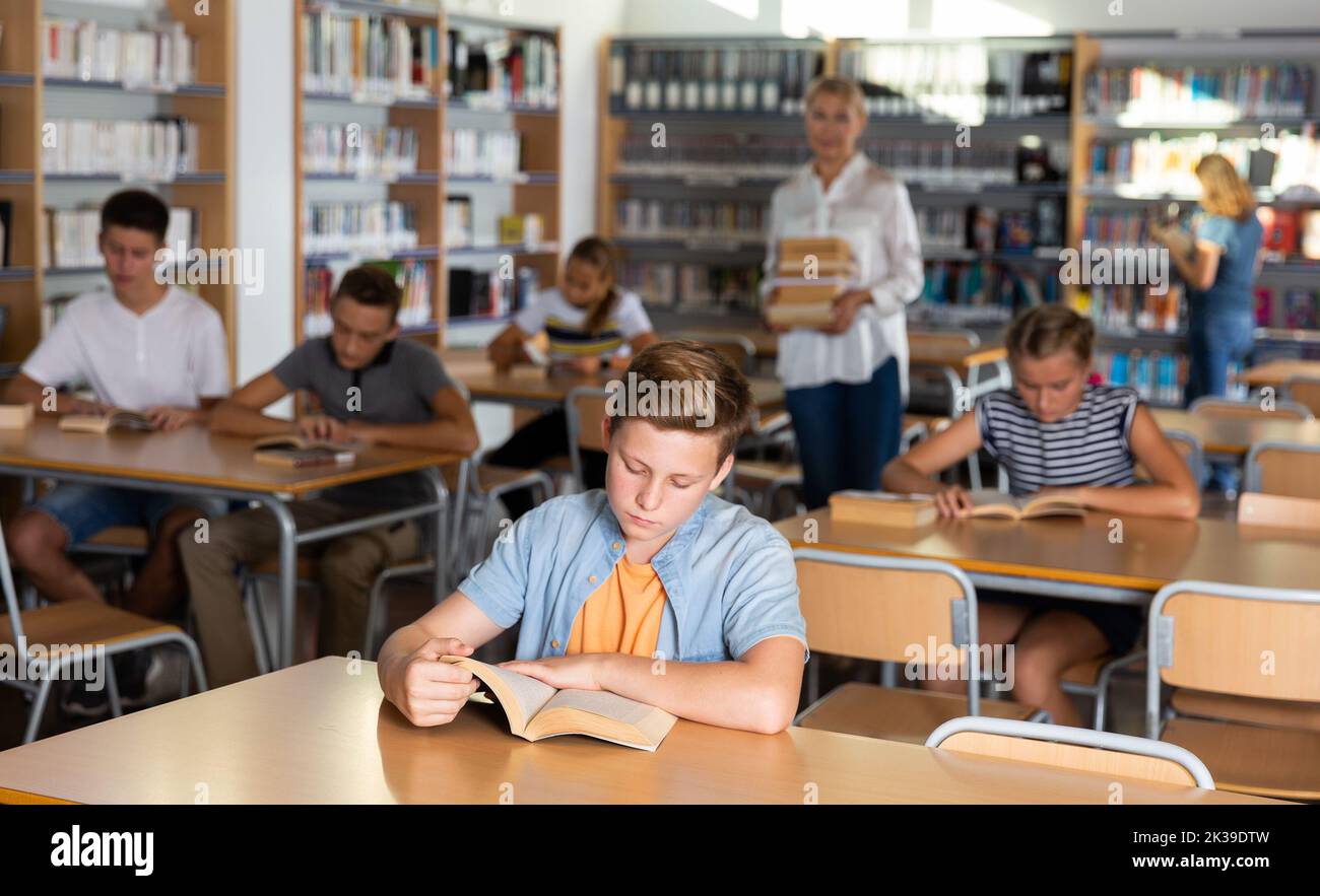 Boy preparing for lesson in school library, reading textbooks Stock ...
