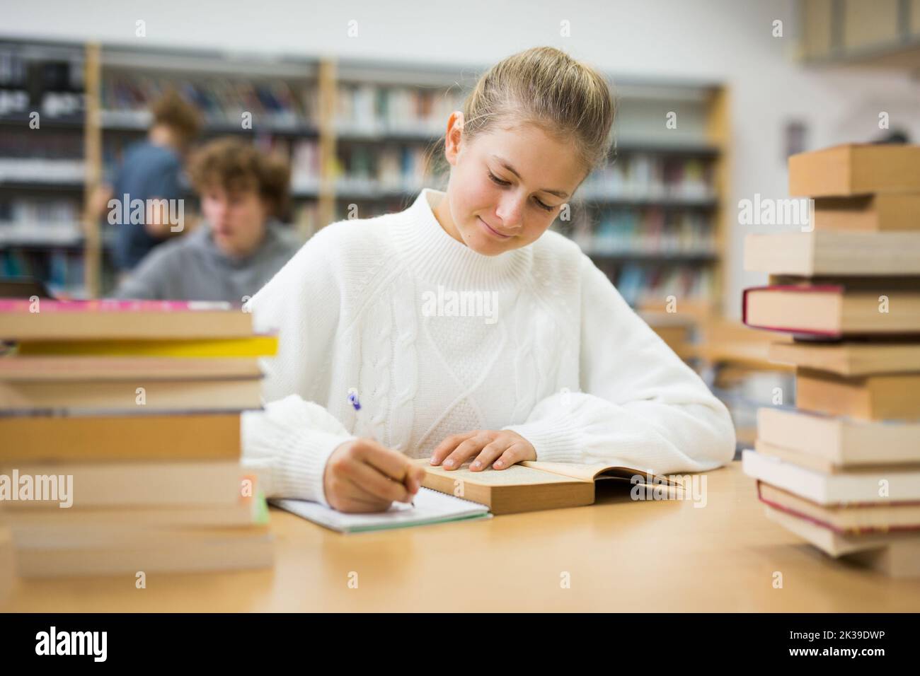 Female teenager engaged in research working with books in library Stock ...