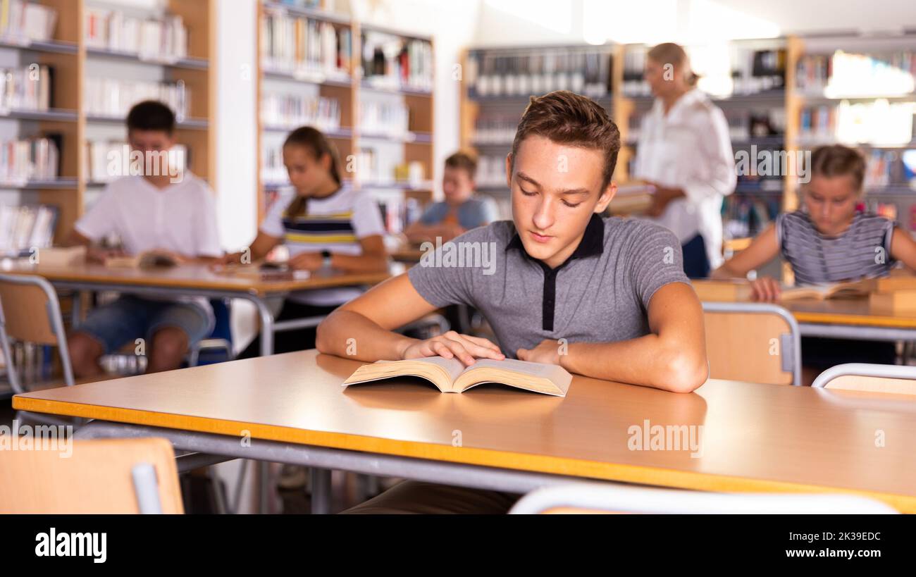 Boy preparing for lesson in school library, reading textbooks Stock ...