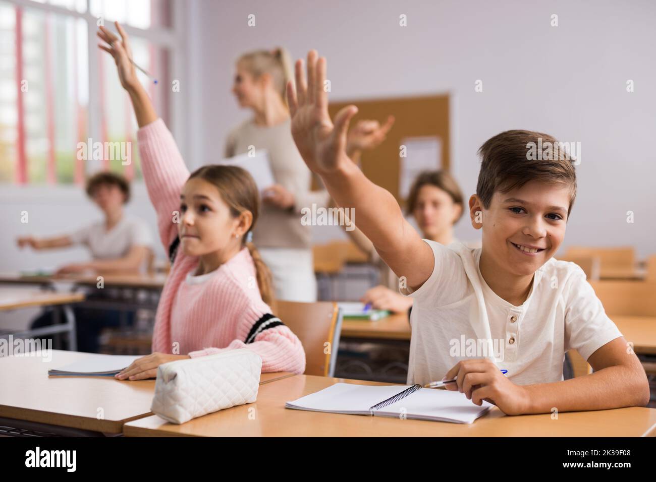 Friendly schoolchildren raise their hand to answer during lesson Stock ...