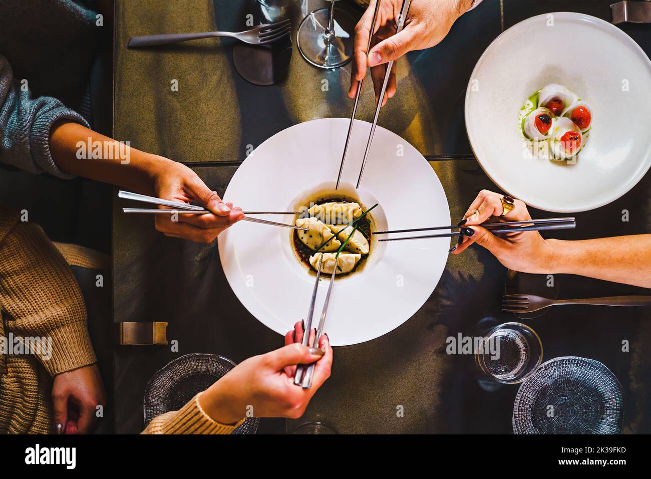 Group of friends picking up a traditional gyoza dumpling at a Japanese ...