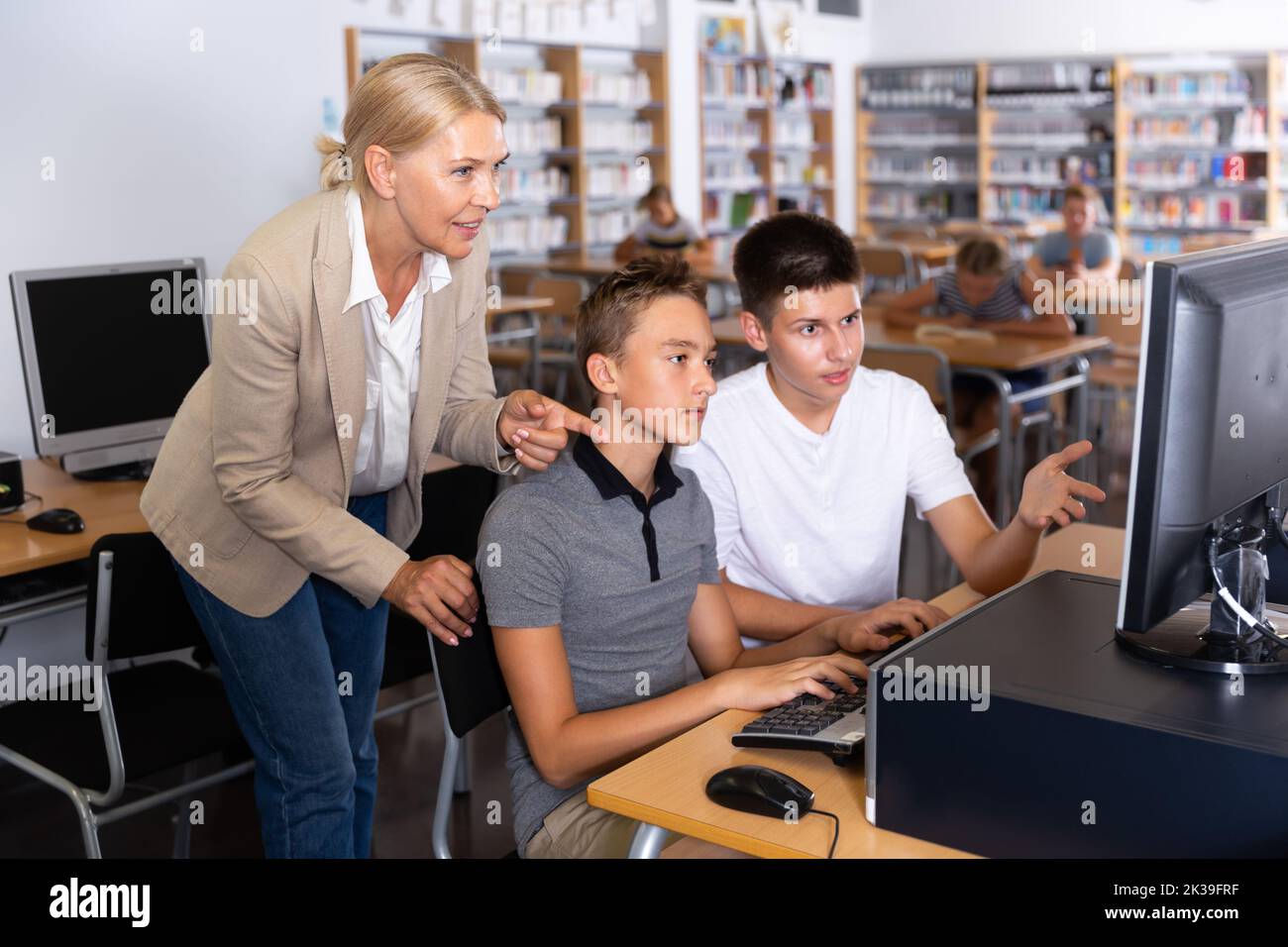 Children and young teacher working with computers Stock Photo - Alamy
