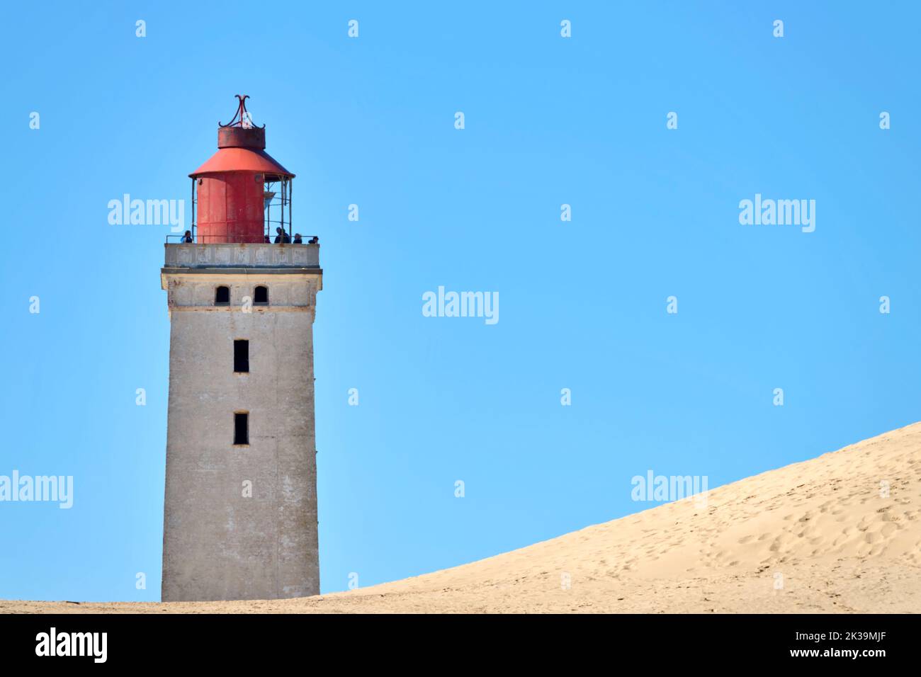 An old lighthouse with weathered walls and people on it surrounded by ...