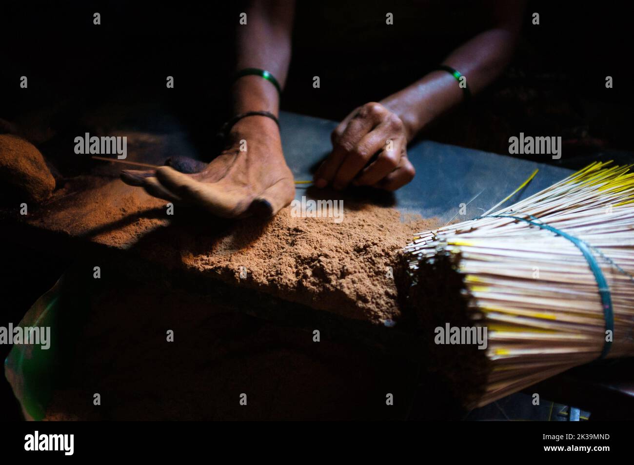 Older Indian Muslim woman making sandal incense sticks from the powder ...