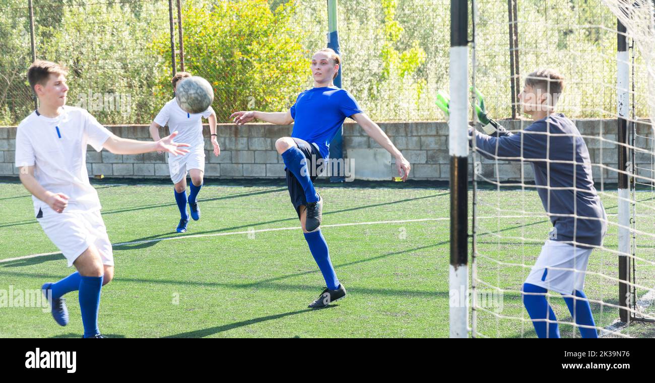 Game of football match between two teams of teenagers in white and blue ...