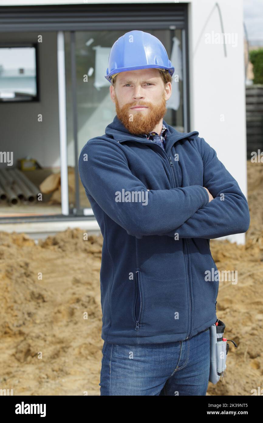 confident young builder posing with folded arms outdoors Stock Photo ...