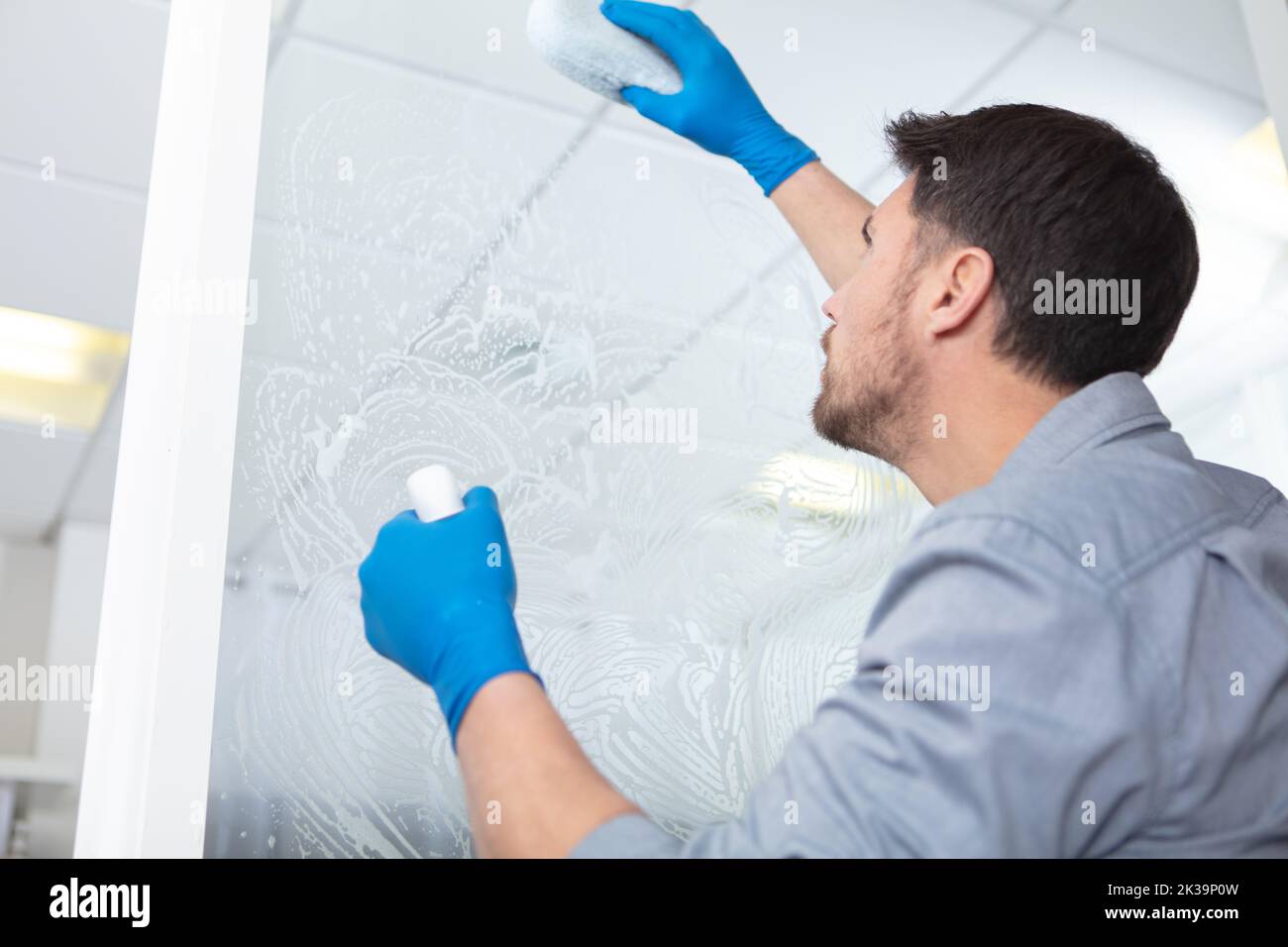 male worker cleaning glass window with sponge Stock Photo - Alamy