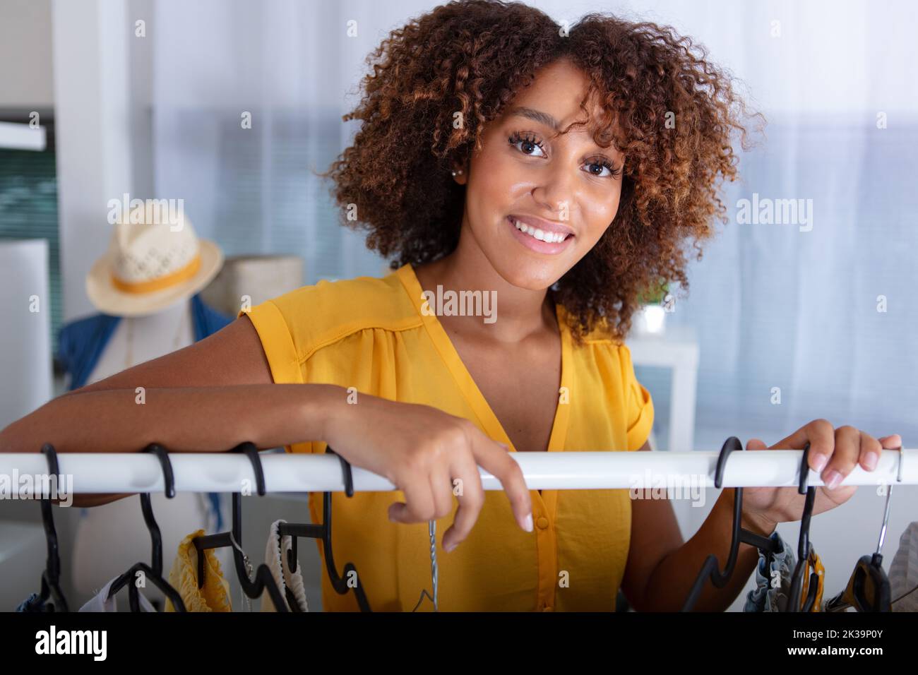 young woman stood behind a rail of clothing Stock Photo - Alamy