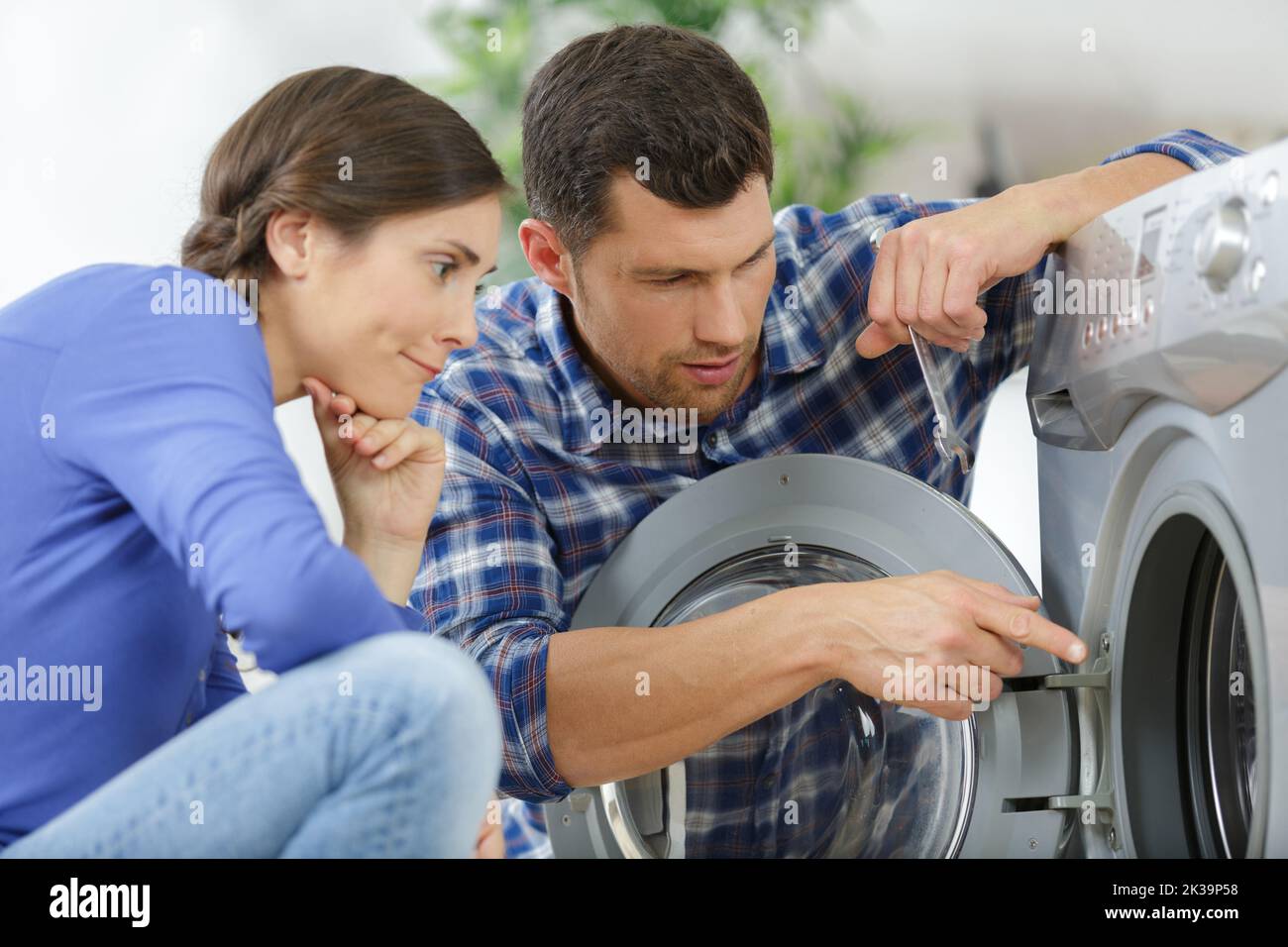 woman with serviceman looking at washing machine Stock Photo - Alamy