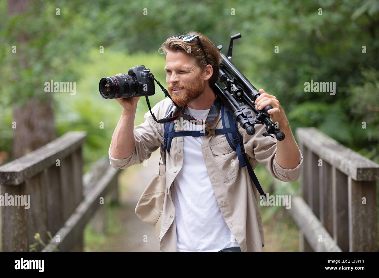 man standing with camera and tripod over his shoulder Stock Photo - Alamy