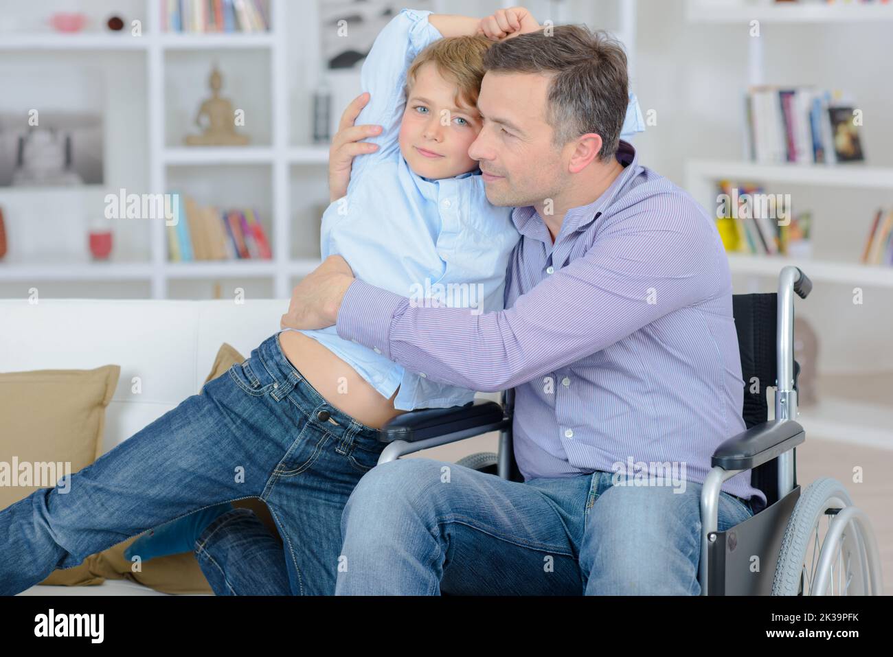 Man in wheelchair cuddling young boy Stock Photo - Alamy