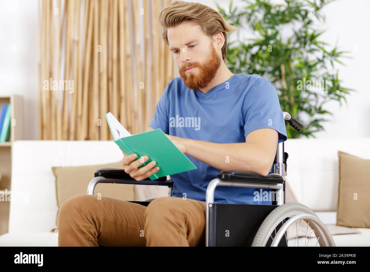 young man in wheelchair reading book indoors Stock Photo - Alamy