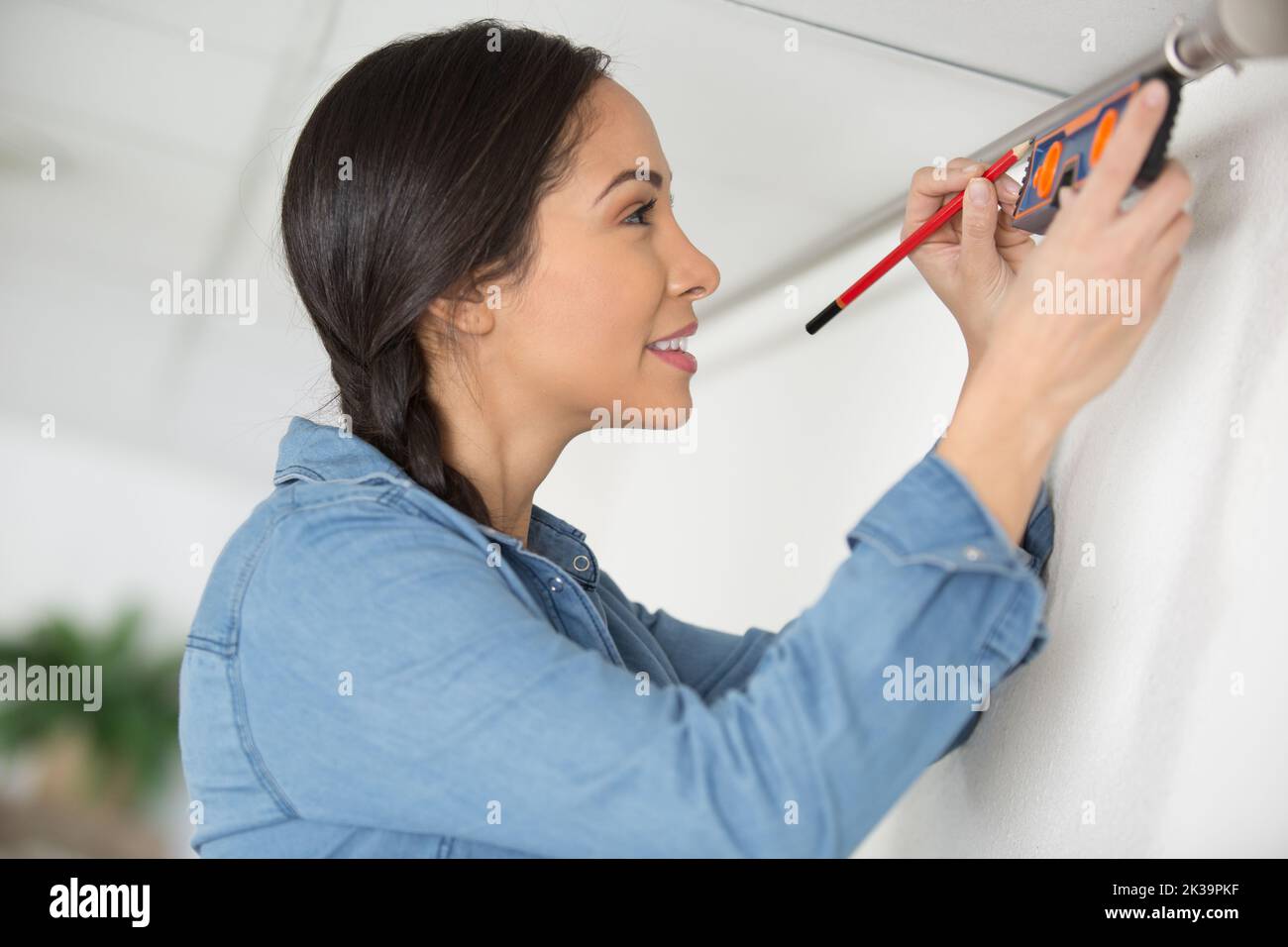 woman using a spirit level on the ceiling Stock Photo - Alamy